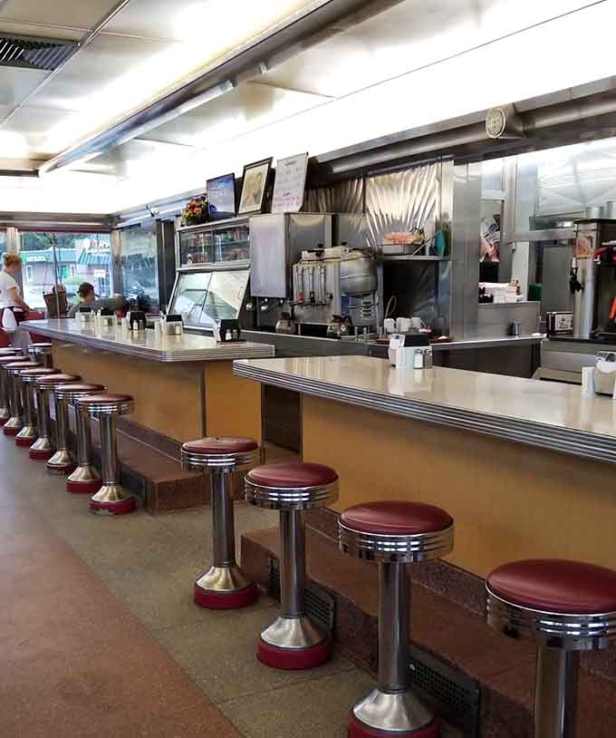 Chrome stools lined up like soldiers, ready to support your breakfast mission with burgundy vinyl comfort.