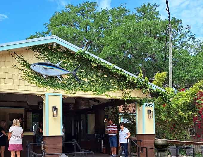That giant fish sculpture diving through the greenery tells you everything about what's on the menu inside this charming spot.