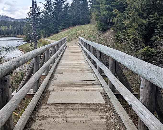 A rustic bridge stretches across tranquil waters, inviting you into mountain scenery that looks straight from a postcard.