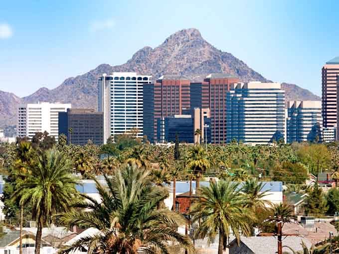 Desert palms frame gleaming buildings with mountain peaks standing guard like nature's own security system in the distance.