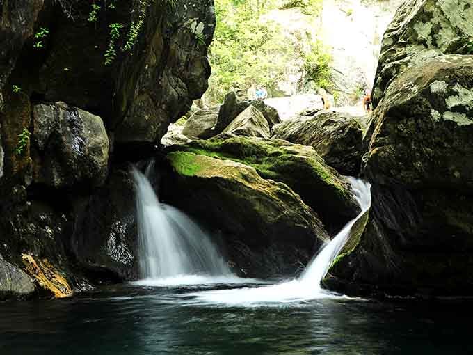 Moss-covered boulders frame cascading water in this secret grotto where light filters through like nature's own cathedral.