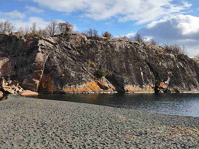 Those dramatic rock formations rising from the dark shore create a landscape that's pure geological poetry in motion.