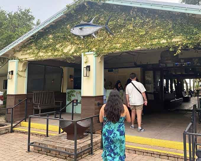 Guests stroll toward the vine-covered entrance where fresh catches and waterfront views await just beyond those welcoming doors.