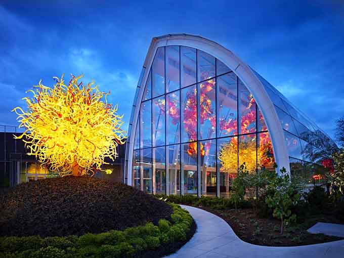 When twilight meets molten glass magic, the glasshouse glows like a jewel box filled with impossible treasures and dreams.