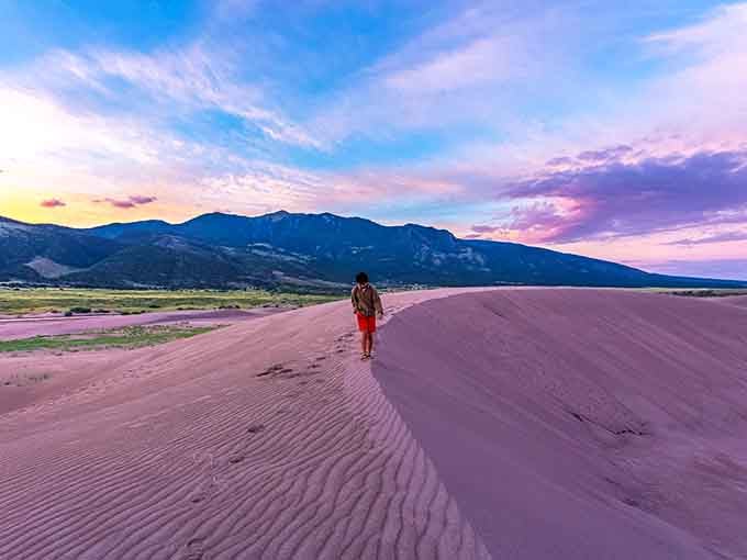 Sunset paints these towering dunes in cotton-candy hues while a lone wanderer experiences the surreal magic of Colorado's desert surprise.