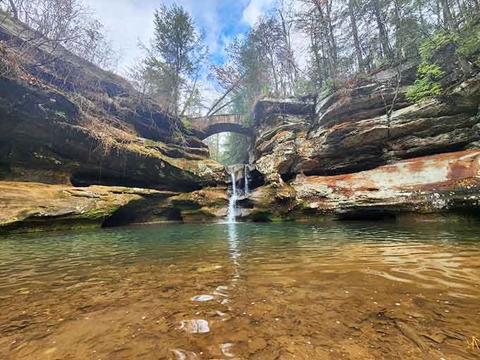 That stone bridge arching over the waterfall creates a scene straight from a storybook adventure.