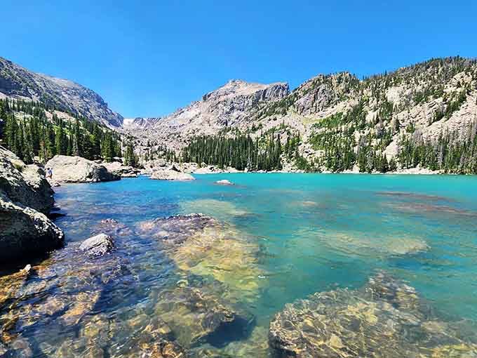 Crystal-clear shallows reveal every pebble beneath the surface, while mountains stand guard like silent sentinels above.