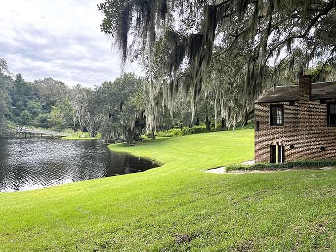 Spanish moss drapes these riverside oaks in silvery elegance, while manicured lawns roll toward tranquil waters below.