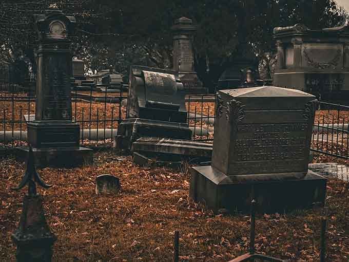 Ornate monuments rest beneath autumn leaves, each carved stone a testament to lives lived generations before us.