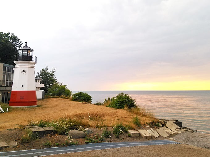 Golden hour paints the sky in sherbet colors while this cheerful lighthouse stands guard over tranquil waters.