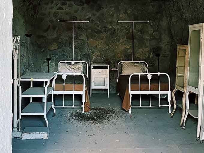 These sparse iron beds and peeling walls tell stories of desert heat and desperate men counting endless days.