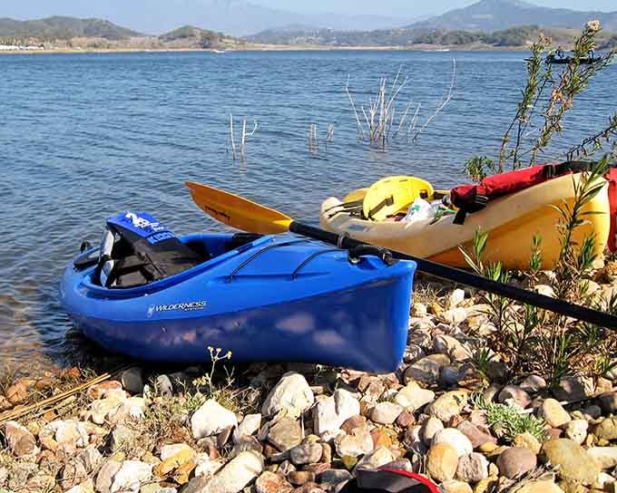 Colorful kayaks lined up on the rocky shore, ready to transform ordinary folks into intrepid explorers for the day.