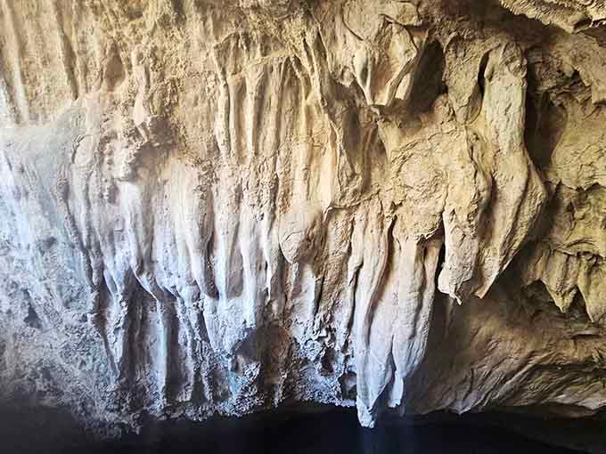 Flowstone formations drape the walls like frozen waterfalls that forgot to keep flowing downward.