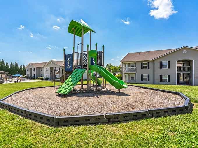 That bright green playground equipment practically glows against blue sky, where kids can actually be kids without scheduling it.