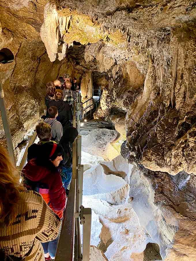 Visitors navigate the narrow walkway past flowstone walls that took millennia to create, making rush hour seem trivial.
