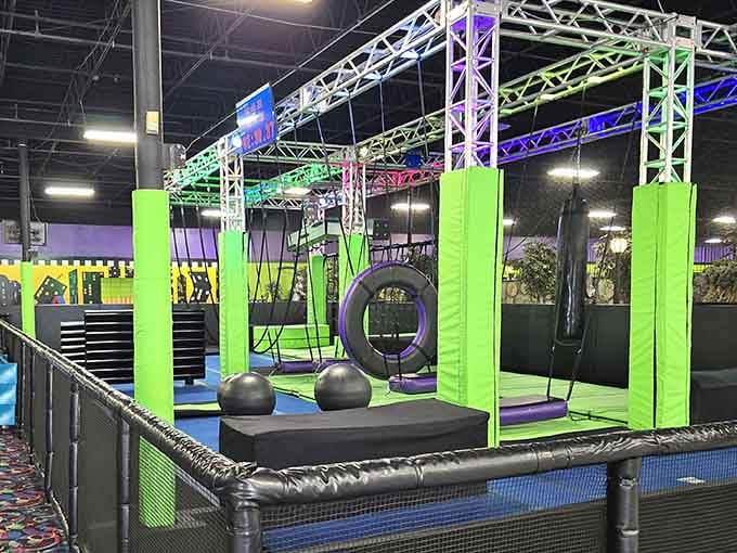 Ninja warrior obstacles tower overhead while dining tables wait below for your inevitable post-conquest pizza celebration.