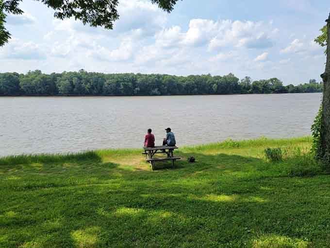 Two visitors soak in the riverside serenity, proving that the best conversations happen with water views and zero distractions.