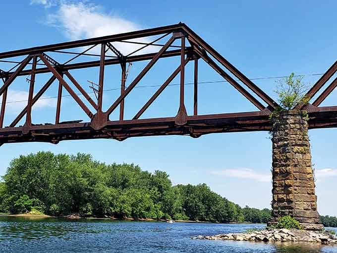 This iron truss bridge stands like a monument to engineering, its stone pier anchoring it firmly to both past and present.