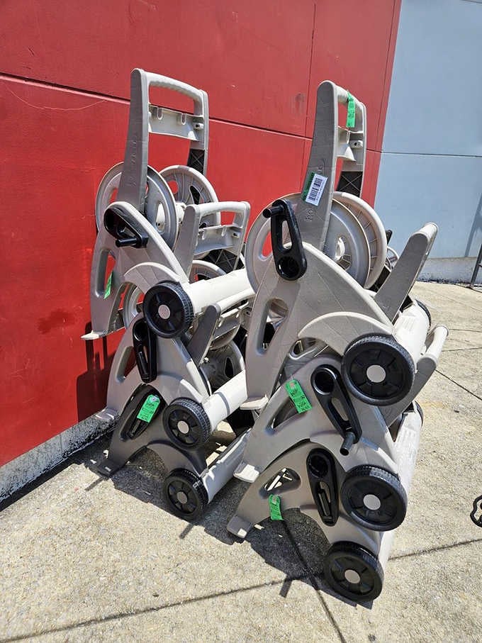 Sturdy hose reel carts basking in the sun, ready to tackle yard work with their multi-wheeled charm and practical gray design.