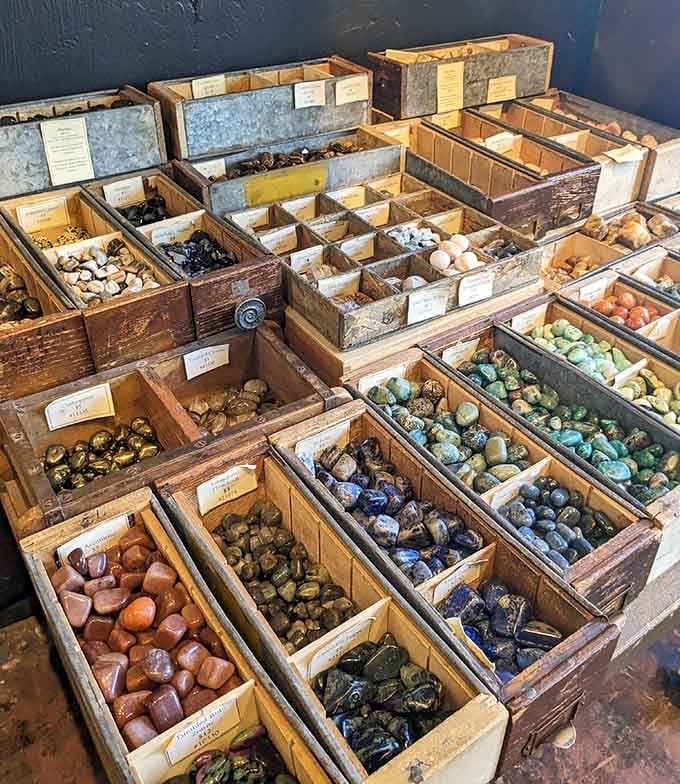 A rainbow of polished stones awaits in weathered wooden boxes, each one a geological love letter.