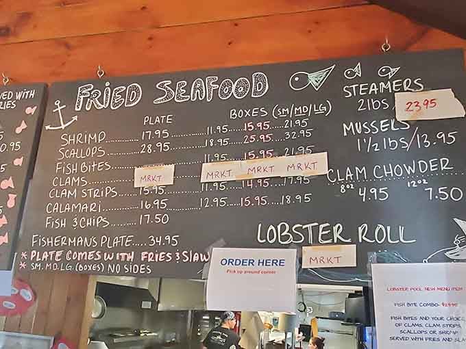 The board is decorated with simple chalk drawings. Below the menu, a glimpse of the kitchen and an "ORDER HERE" sign suggests a casual, counter-service atmosphere.