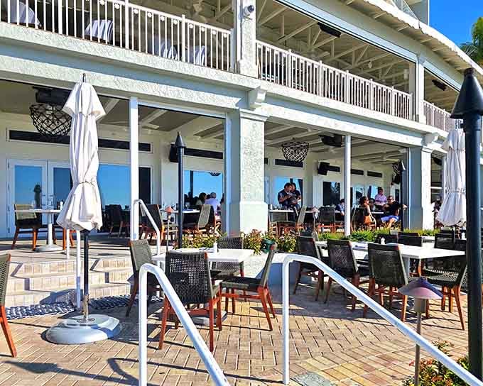 Two-story waterfront elegance with white umbrellas dotting the terrace like sailboats anchored in a sea of good taste.