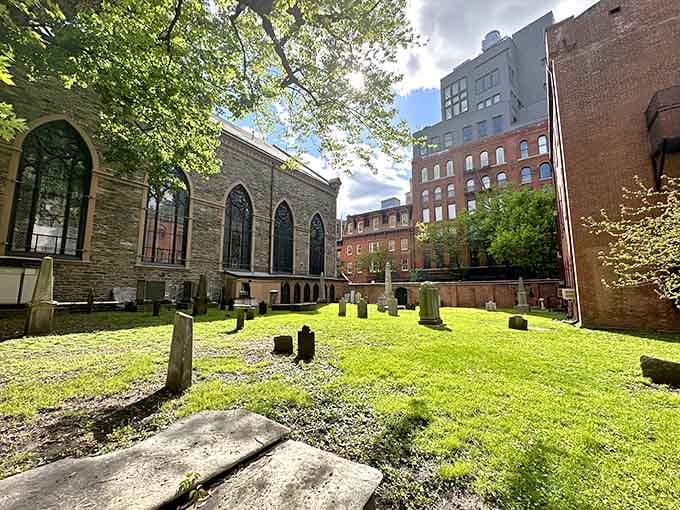 Sunlight streams through trees onto centuries-old headstones, a peaceful pocket of history amid Manhattan's bustle.
