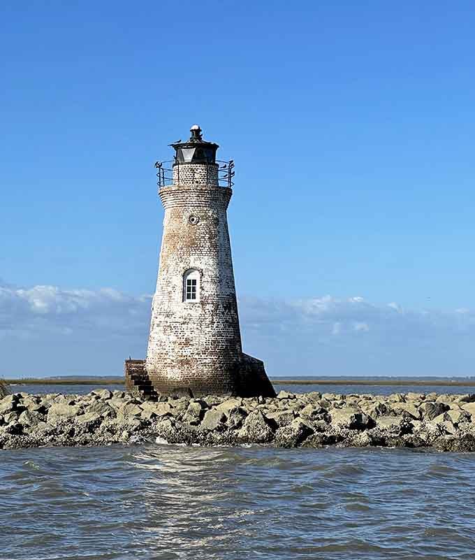 Standing alone on its rocky island perch, this weathered sentinel has clearly earned its retirement with dignity and grace.