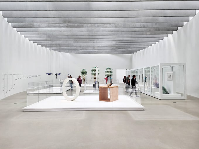 Clean white galleries showcase glass art under dramatic ceiling installations that look like frozen waves of light.