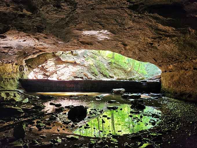 The cave's twin entrance frames flowing water and green reflections in a scene straight from Middle Earth.