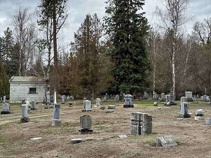 Winter's bare branches frame weathered markers and a small mausoleum, where history rests beneath overcast Pacific Northwest skies.