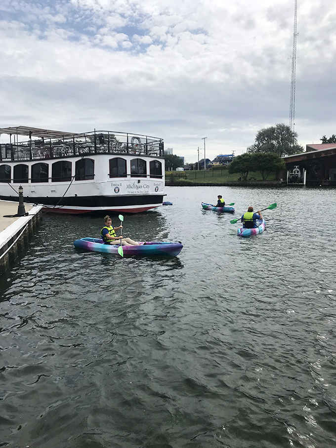 Paddlers glide peacefully past a classic riverboat while exploring calm waters perfect for a lazy afternoon adventure.