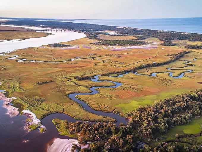 Golden marshlands weave through the landscape like nature's own watercolor painting, stretching toward the shimmering Atlantic horizon.
