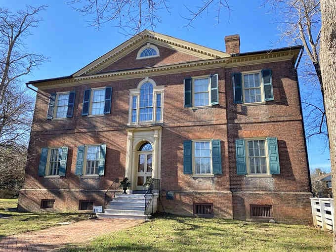 This elegant Georgian mansion radiates Southern charm with its perfect symmetry and stately brick facade gleaming in afternoon light.
