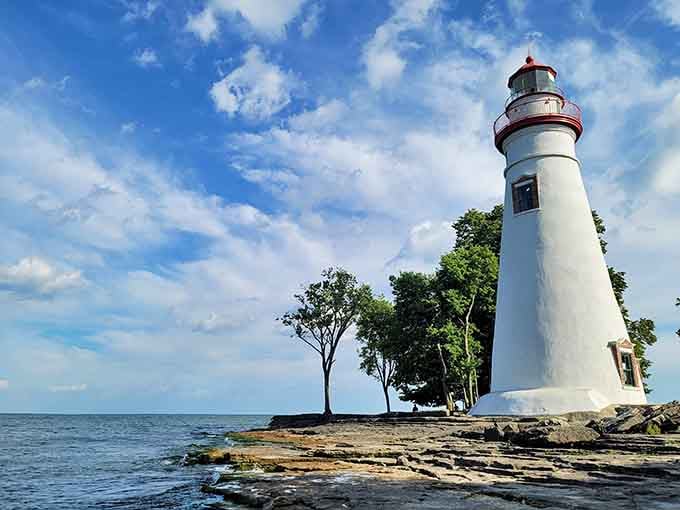 Standing tall on rocky shores, this elegant white tower reaches skyward with timeless grace and beauty.
