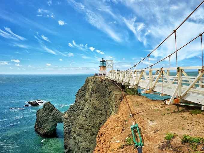 That suspension bridge swaying over churning waters makes reaching this lighthouse feel like a proper coastal adventure unfolds.