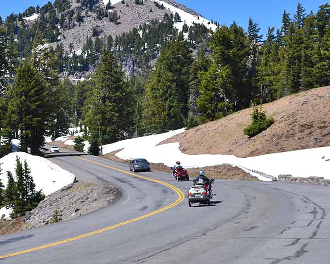 Summer snow banks tower beside the pavement, creating nature's own tunnel through the high country.