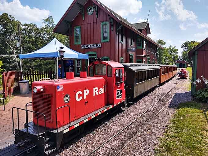 That cheerful red miniature locomotive waits beside the historic depot, ready to delight passengers of all ages today.