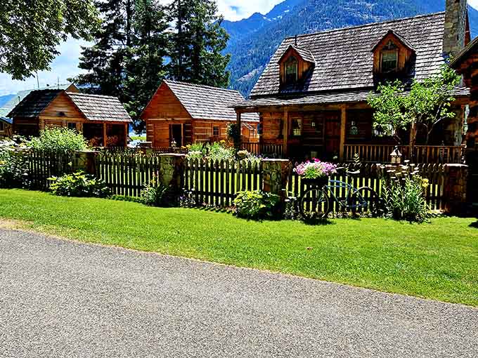 Charming log cabins with picket fences nestle beneath mountain peaks, looking like they escaped from a Swiss postcard.