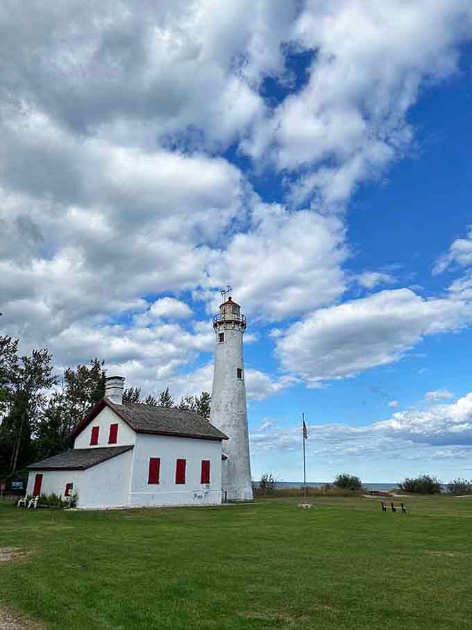 Clouds drift lazily over this pristine white sentinel, where red shutters pop like cherries on vanilla ice cream.