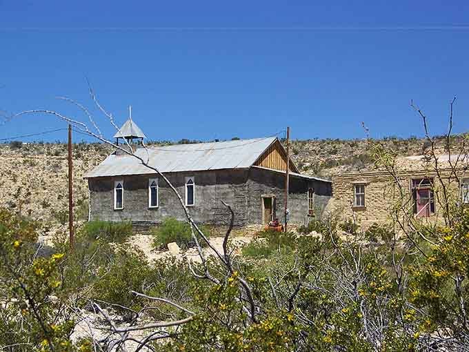 Desert wildflowers bloom around this weathered stone building, proving beauty persists even in abandoned places.