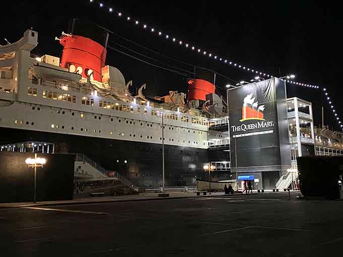 The Queen Mary's red funnels pierce the night sky, a floating palace turned permanent resident of Long Beach's waterfront.