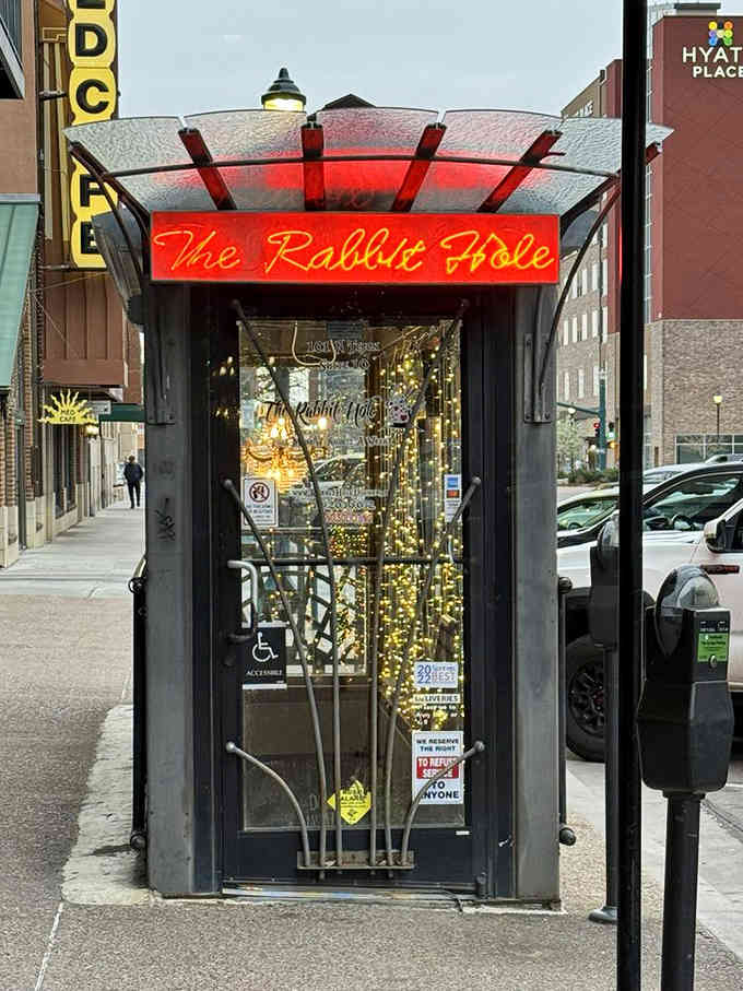 That glowing red sign beckons like a beacon for anyone curious enough to follow Alice.