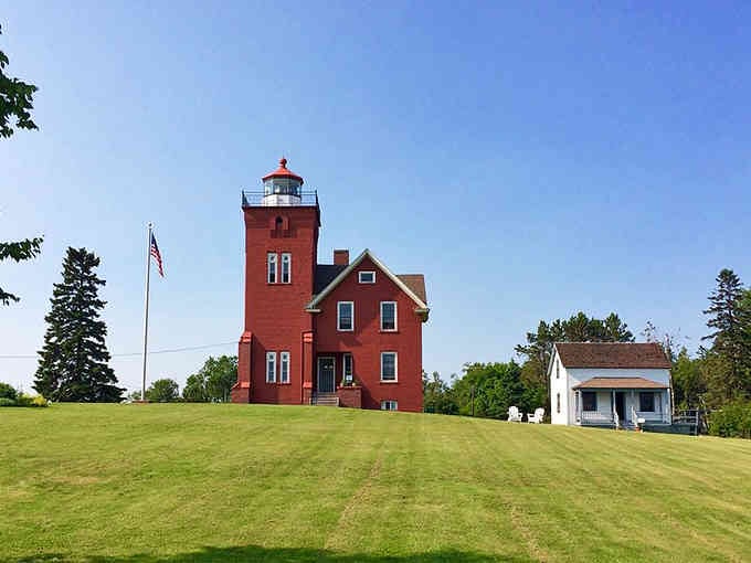 Minnesota's oldest working lighthouse glows brick-red against emerald lawns, a Victorian beauty that's still earning its keep today.
