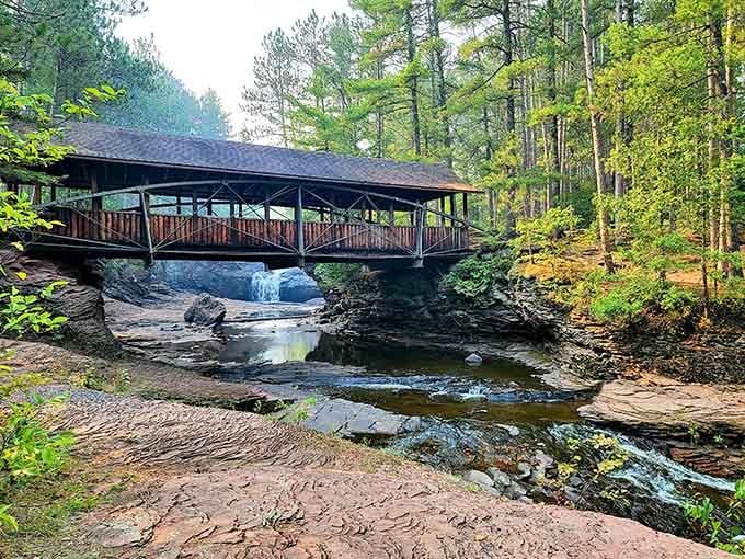 A covered bridge over cascading falls feels like stepping into a postcard where nature does all the heavy lifting.