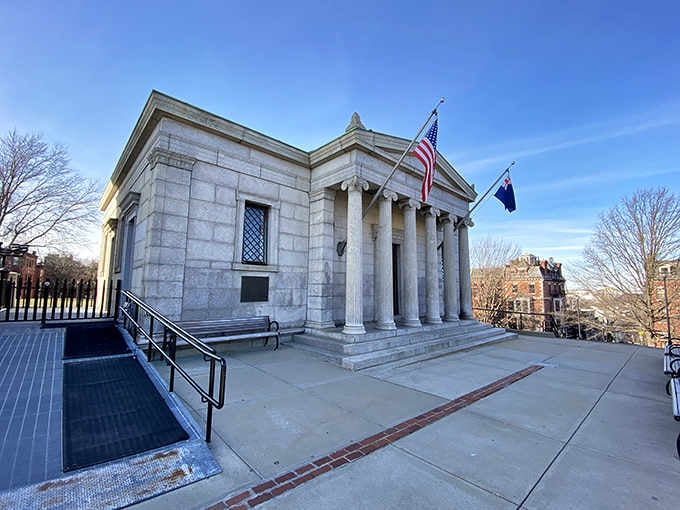 Classical columns frame the entrance to this memorial building, where dignity and remembrance meet under open skies and flags.