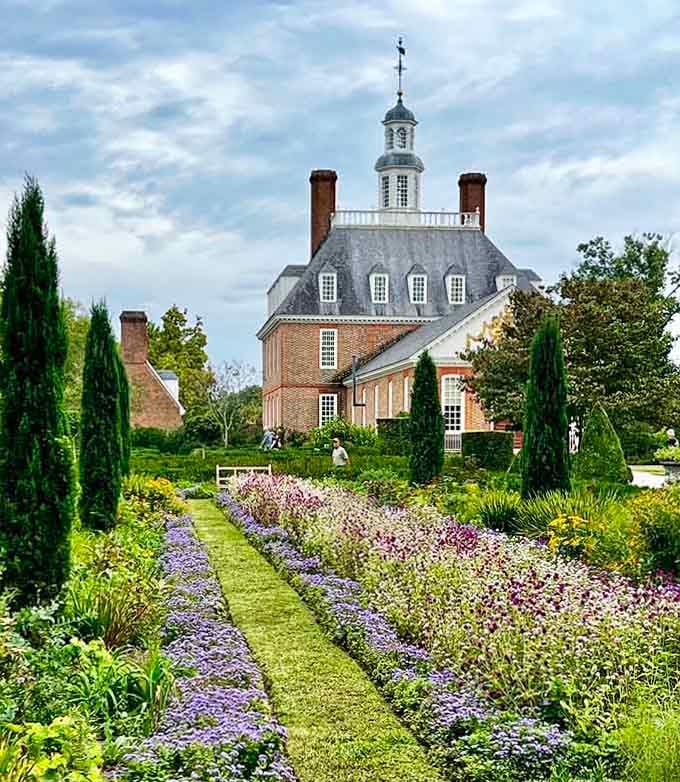 The formal gardens burst with purple and pink blooms, creating a living tapestry of colonial elegance.