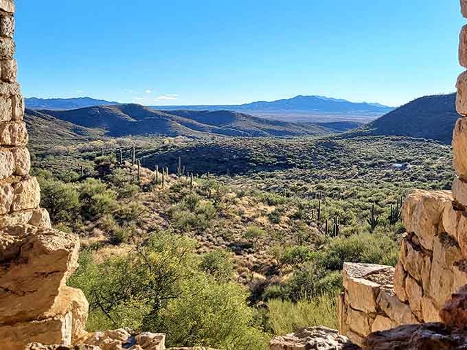 From inside the cave looking out, layers of desert mountains stretch endlessly under that impossibly blue sky.