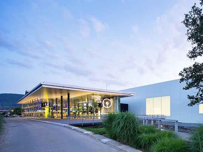 The museum glows at twilight, its modern glass walls revealing treasures inside like a jewel box opening wide.