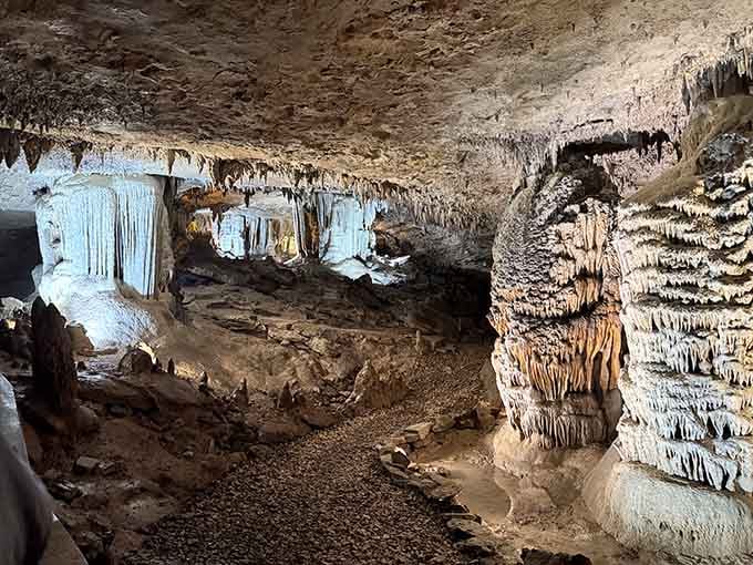 The cave's ceiling drips with ancient formations while columns rise like frozen waterfalls in stone.
